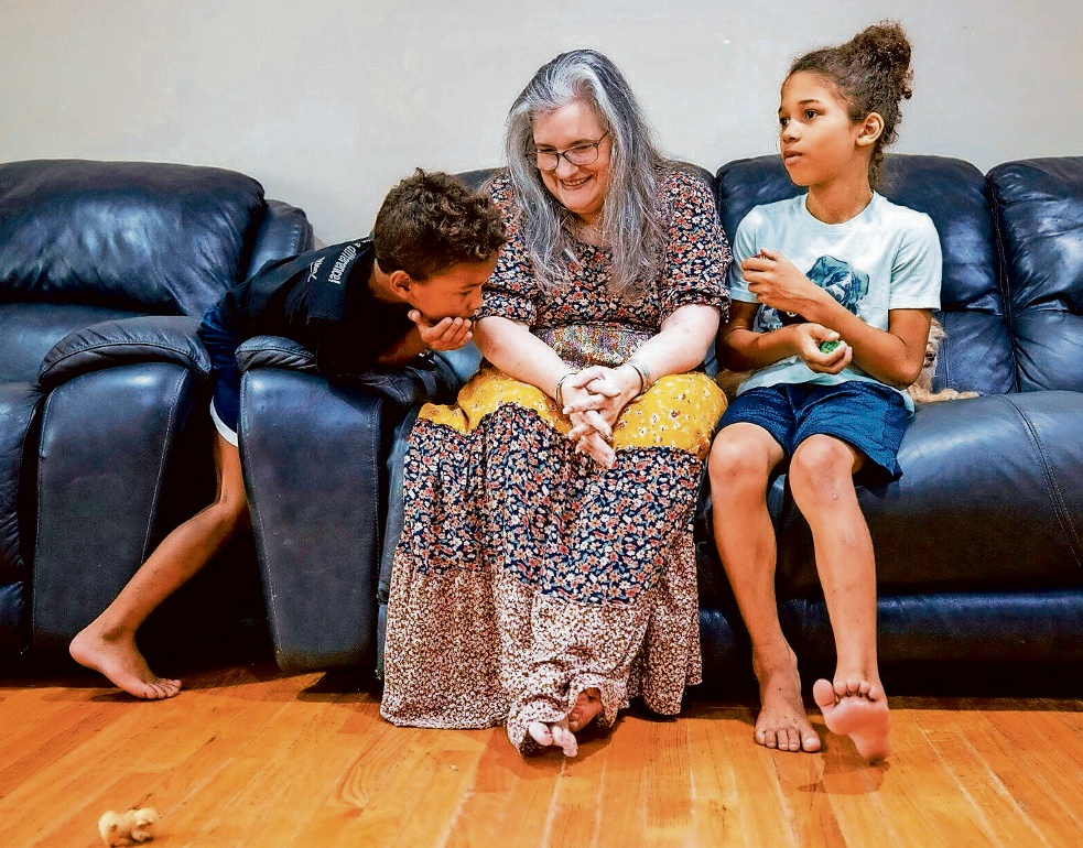 Cindy Bogan-Baber (center) laughs while sitting on the couch and ...