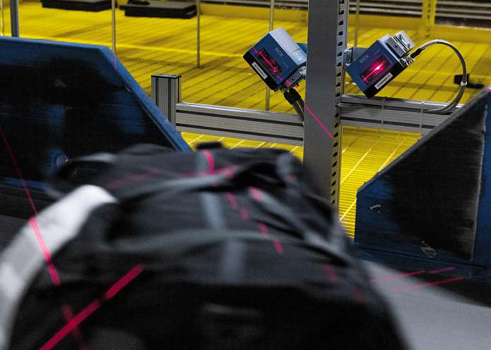 an automatic tag reader reads a baggage tag to make sure it gets on the ...